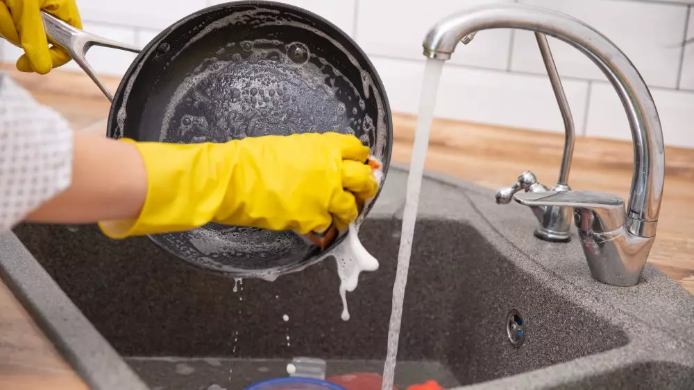 Limpando uma panela na pia da cozinha