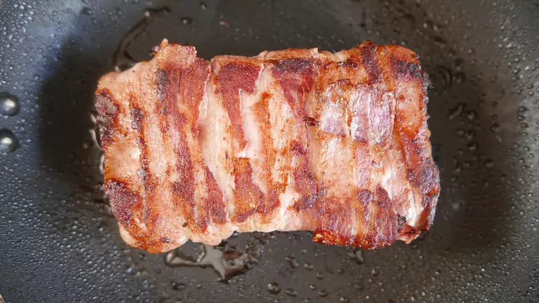 Panino avvolto con pancetta che cucina in padella