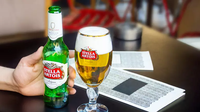 En flaske Stella Artois ved siden av en beger med skjenket øl