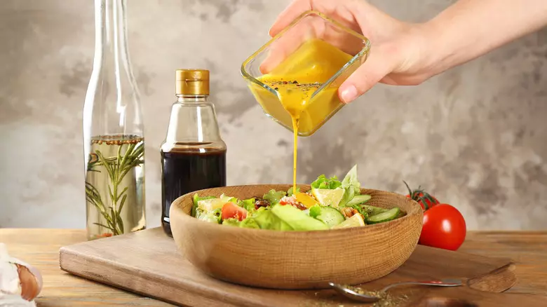 Tangan pouring salad dressing