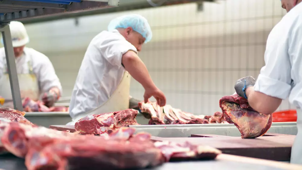 gruppe slagtere, der arbejder på råt kød i slagterbutik