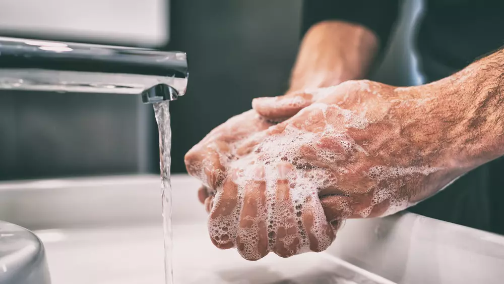 ผู้ชายกำลังล้างมือที่อ่างล้างจาน