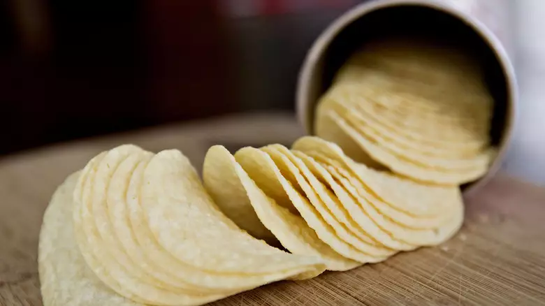 Oop blikkie pringles met skyfies wat op tafel mors