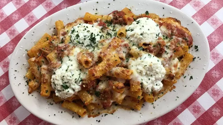 Pasta Rigatoni al horno sobre mantel a cuadros en Buca di Beppo