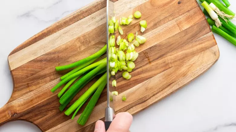 mengiris daun bawang setengah cincang di talenan