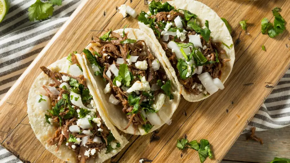 Barbacoa tacos pẹlu cilantro, orombo wewe, alubosa ati iyẹfun tortillas