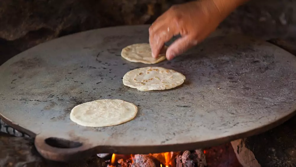 Tortilleria, Person, die Tortillas auf einem Comal herstellt