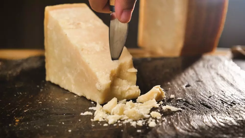 сыр пармезан и нож для сыра на деревянной доске