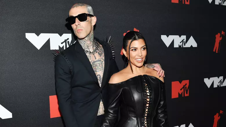 Travis Barker dan Kourtney Kardashian berpakaian hitam di atas permaidani merah