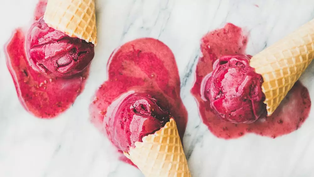 Berry ice cream scoops melting rau ntawm marble countertop