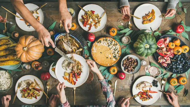 Thanksgiving bord med kalkon och sidor, händer som delar