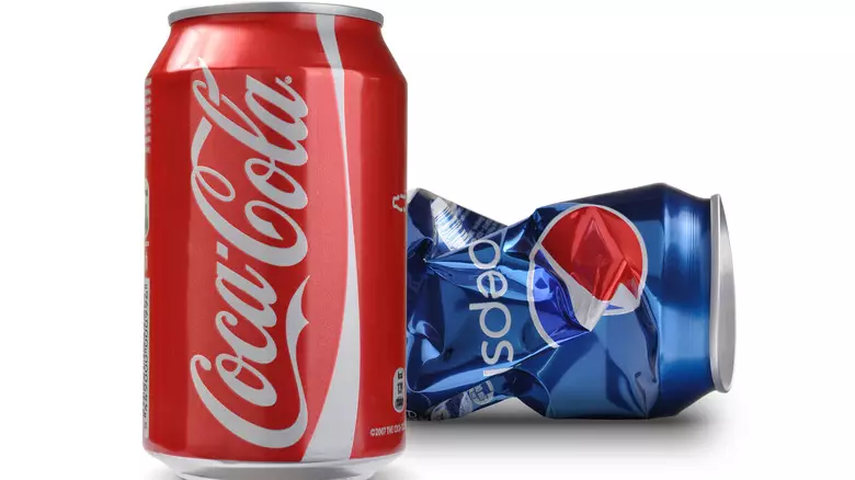 Cola-boks foran en sammenkrøllet Pepsi-boks