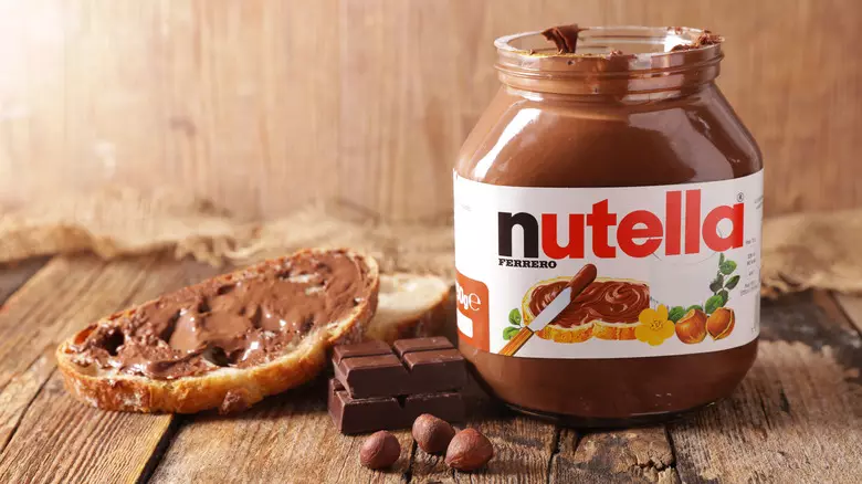 Idẹ ti Nutella lẹgbẹẹ tositi ati awọn ọpa ṣokolaiti