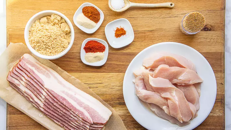 slanina, piščančje meso, začimbe in rjavi sladkor na leseni deski za rezanje