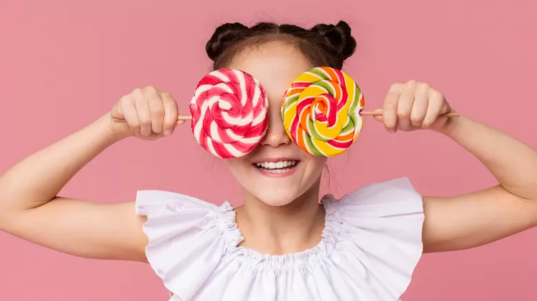 Ọdọmọbìnrin ti o mu awọn lollipops ni iwaju oju rẹ