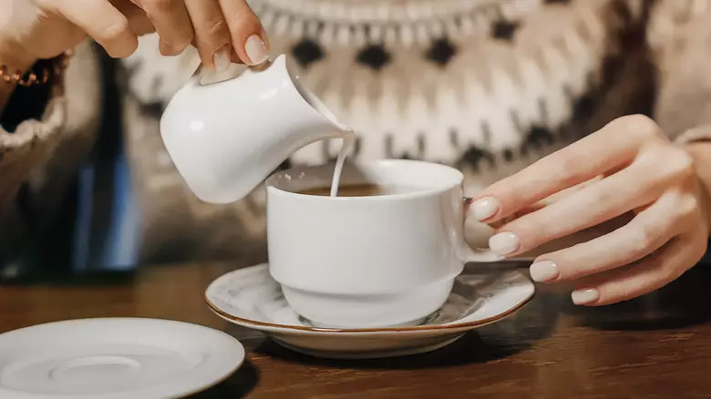 Persona vertiendo una crema en su café