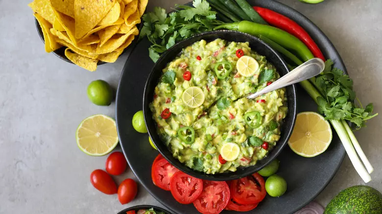 Tigela preta de guacamole com frutas cítricas