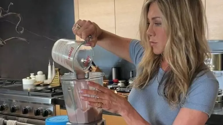 Jennifer Aniston menuangkan smoothie