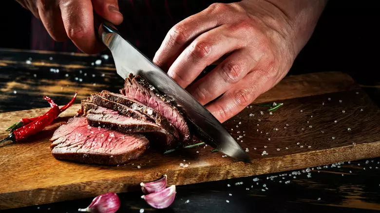 Hände mit einem Messer zum Schneiden von Fleisch