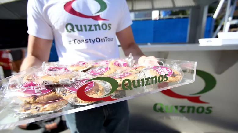 Người đàn ông mặc áo sơ mi Quiznos mang theo những món quà từ cửa hàng