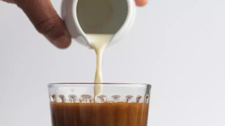 Le lait est versé dans un verre de café