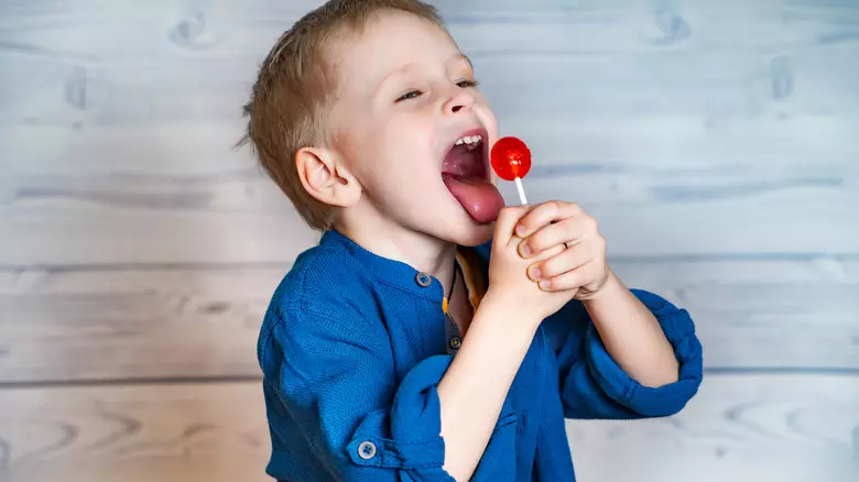 'n Jong seun met sy mond oop om 'n suigstokkie te lek