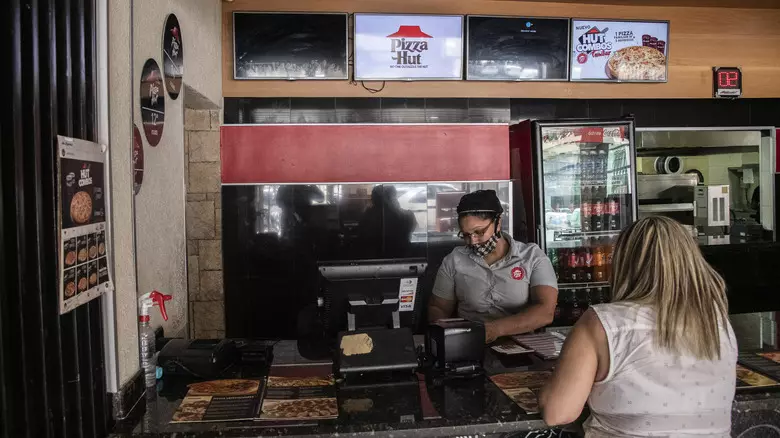 punonjës që pret klientin në Pizza Hut