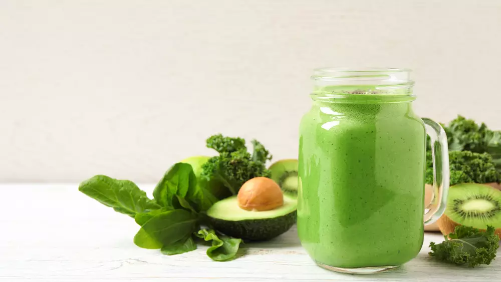 Smoothie hijau di sebelah kangkung, bayam, kiwi dan alpukat