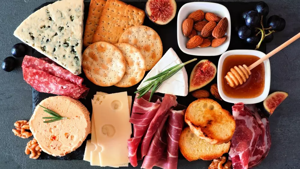 Charcuterie board bil-ġobon, laħmijiet, lewż, frott, u għasel