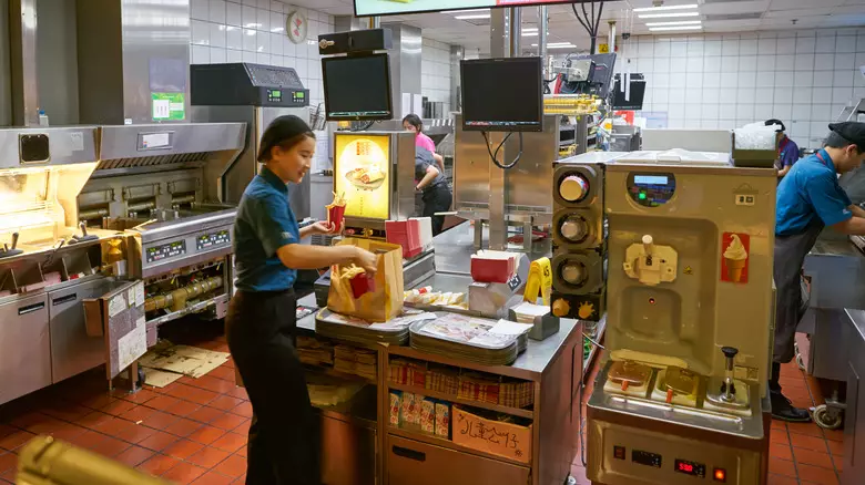 Mcdonald's darbinieks virtuvē ar frī kartupeļiem