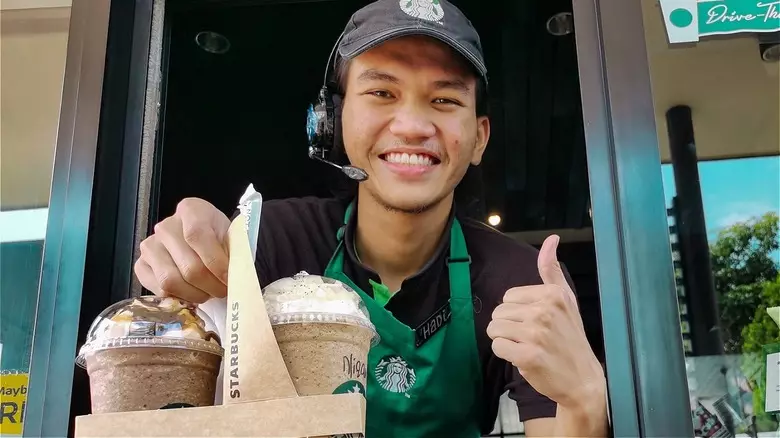 Pracovník Starbucks dává palec nahoru a rozdává nápoje