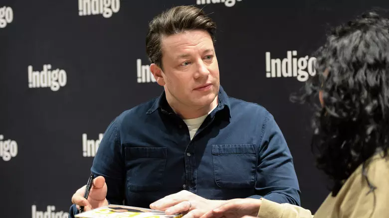 Jamie Oliver subskribanta libron por adoranto