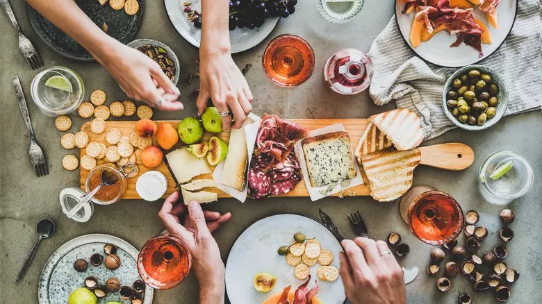 táboa de queixos con salame, queixo azul, tostadas, froitas e copas de viño rosado