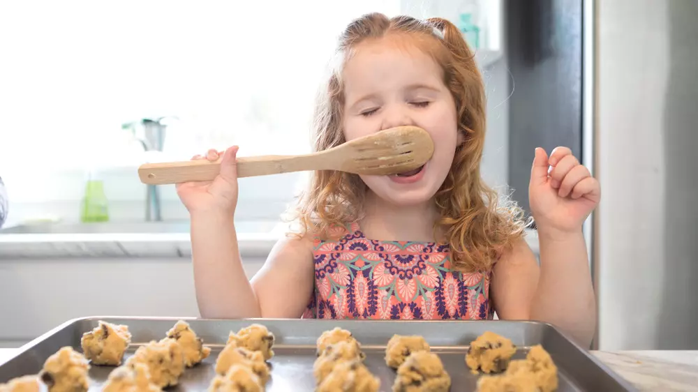 fille mangeant de la pâte à biscuits crue