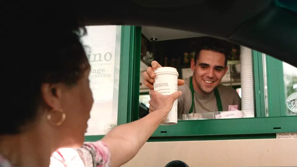 pekerja pandu lalu starbucks menyerahkan kopi kepada orang