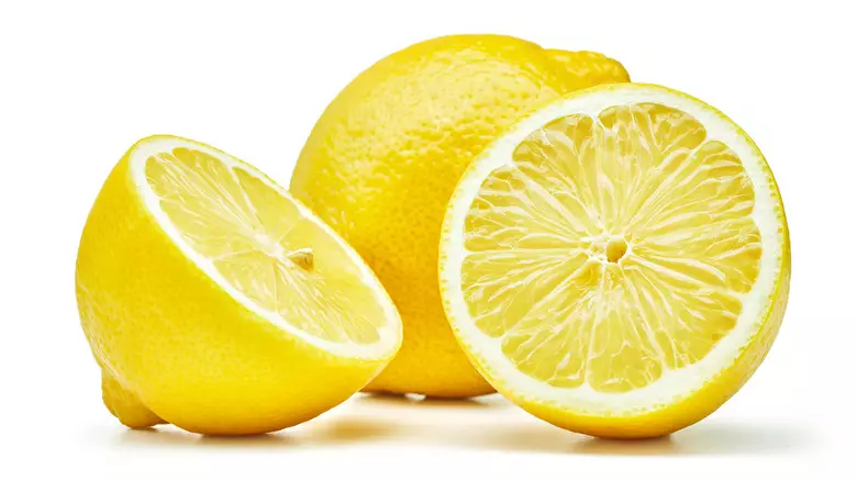 Lemon utuh dan dihiris pada latar belakang putih