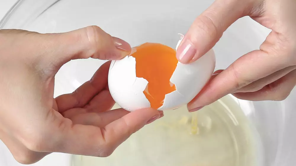 Ruka držící dvě vejce praskání