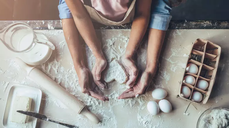 Майка помага на детето да оформя тесто за печене