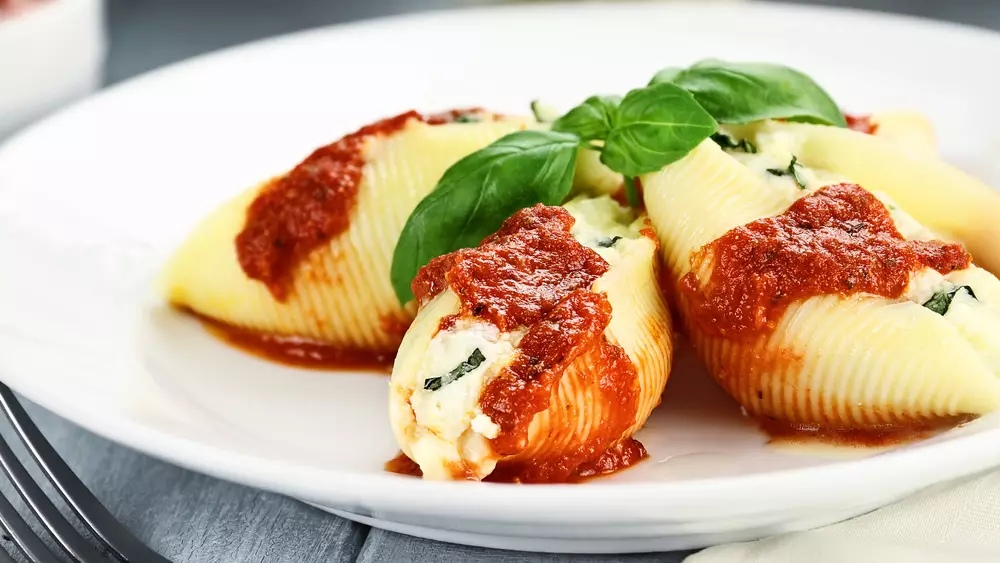 closques de pasta farcides sobre plat blanc amb salsa vermella