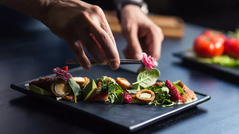 Plan rapproché des mains d'un chef plaquant un plat