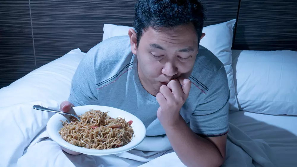 Lalaking kumakain ng noodles sa kama