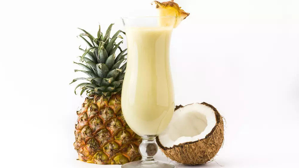 pina colada på hvit bakgrunn med ananas og kokos ved siden av