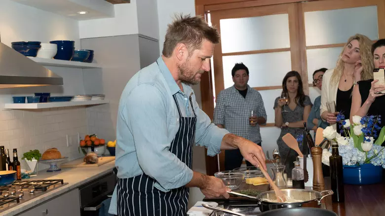 Curtis Stone lagar mat med människor som tittar i bakgrunden