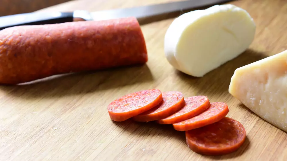 Bıçaq və pendirlər ilə göyərtədə dilimlər ilə pepperoni