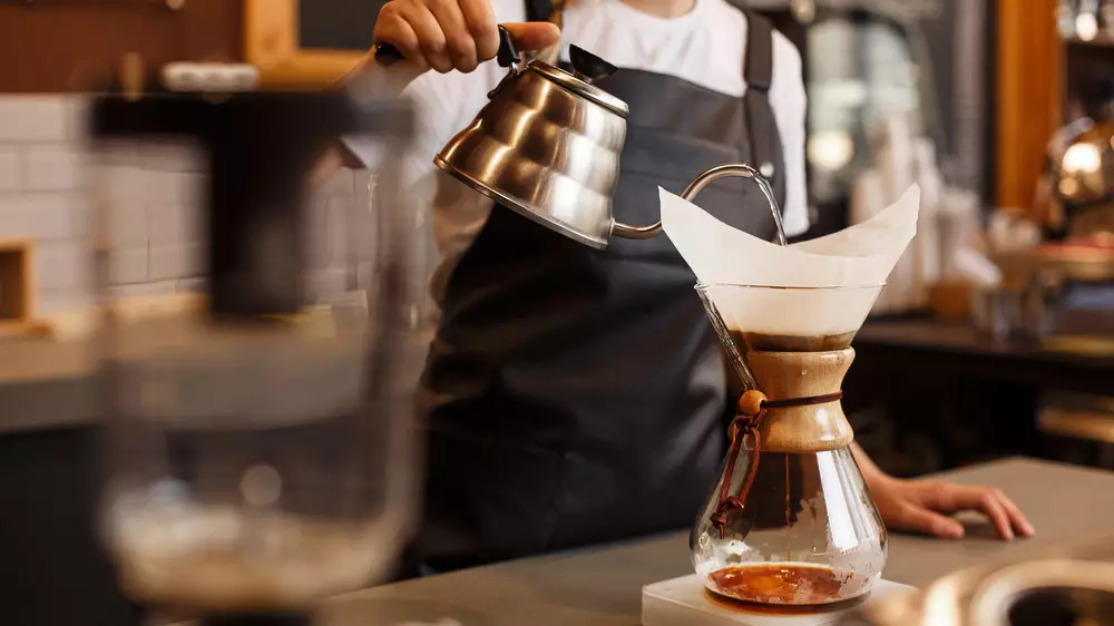 Persona vertiendo agua sobre un café