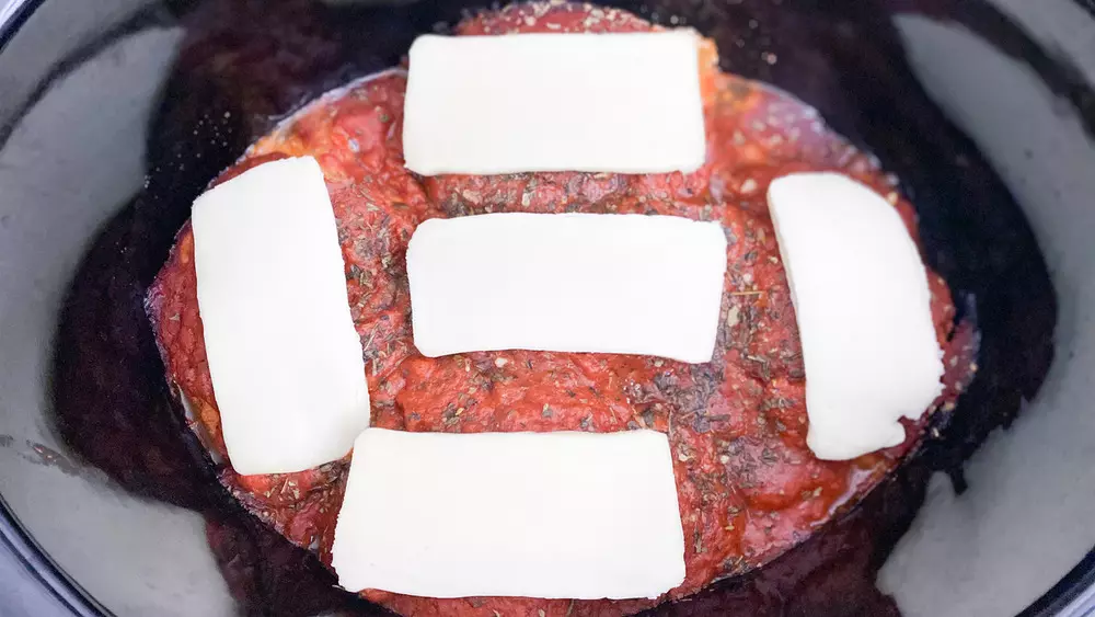 fette di mozzarella adagiate sopra la salsa di pasta che ricoprono i petti di pollo in una pentola a cottura lenta