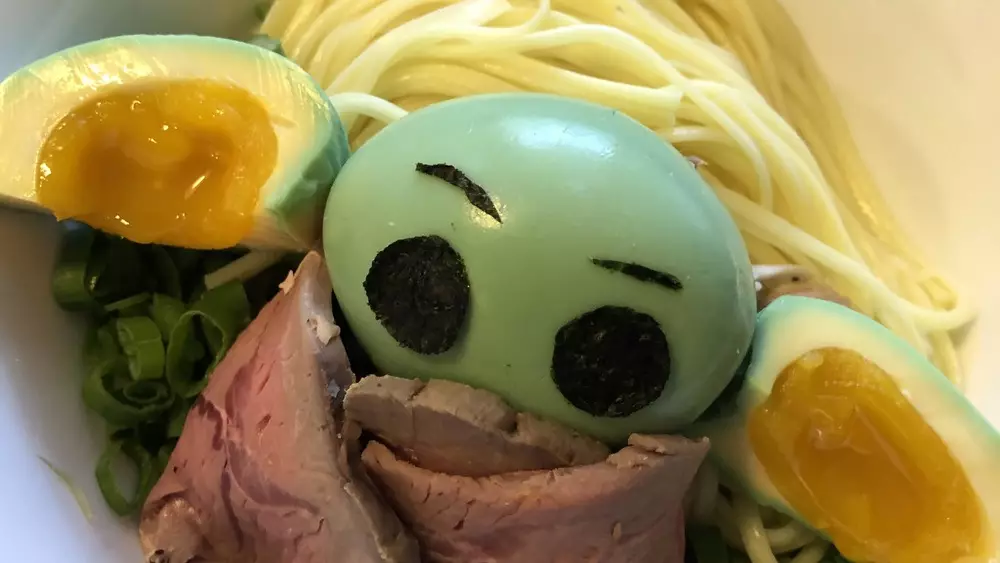 Baby Yoda hecho de huevo verde, orejas con yemas, abrigo hecho de carne de res, en un tazón de fideos