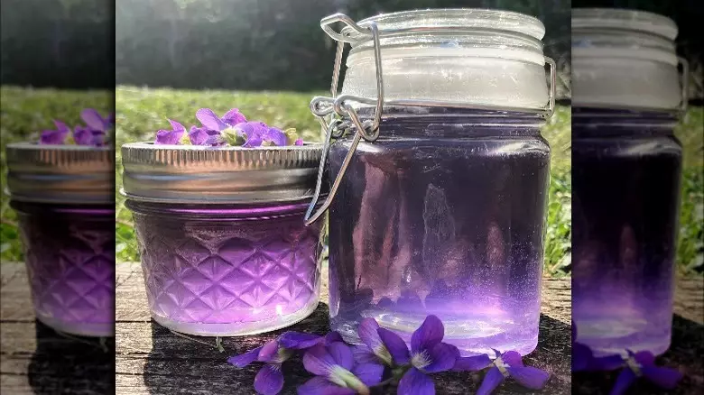 un frasco de jarabe de violeta, otro frasco de vidrio lleno de pétalos de violeta