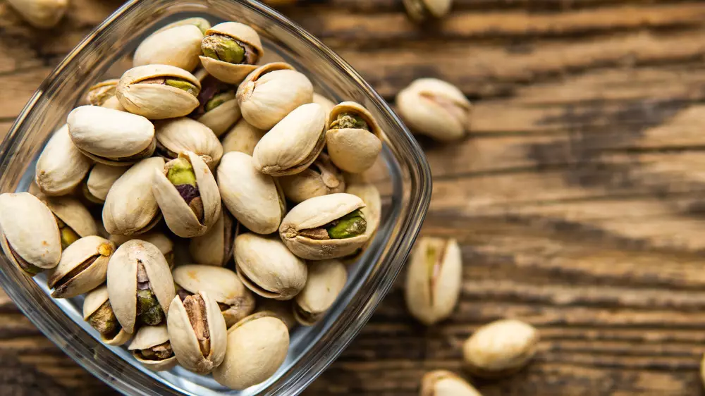 Li-pistachios ka sekotlolo sa khalase holim'a tafole ea lehong