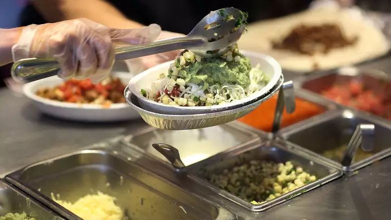 Chipotle Aarbechter setzt Mais Salsa an enger Burrito Schossel